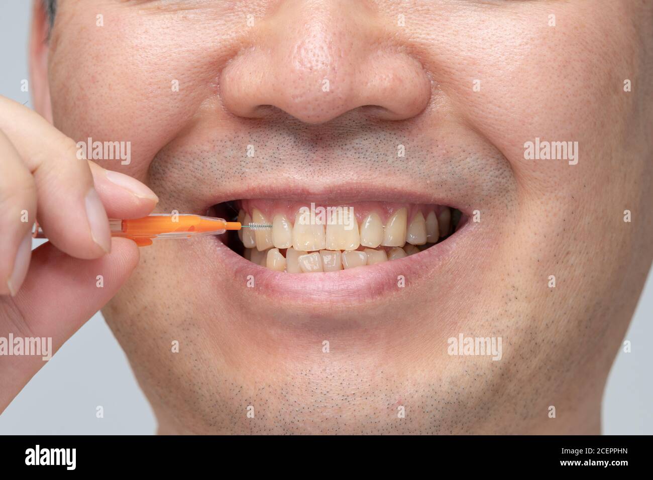 Man cleaning his teeth with an interdental brush Stock Photo - Alamy