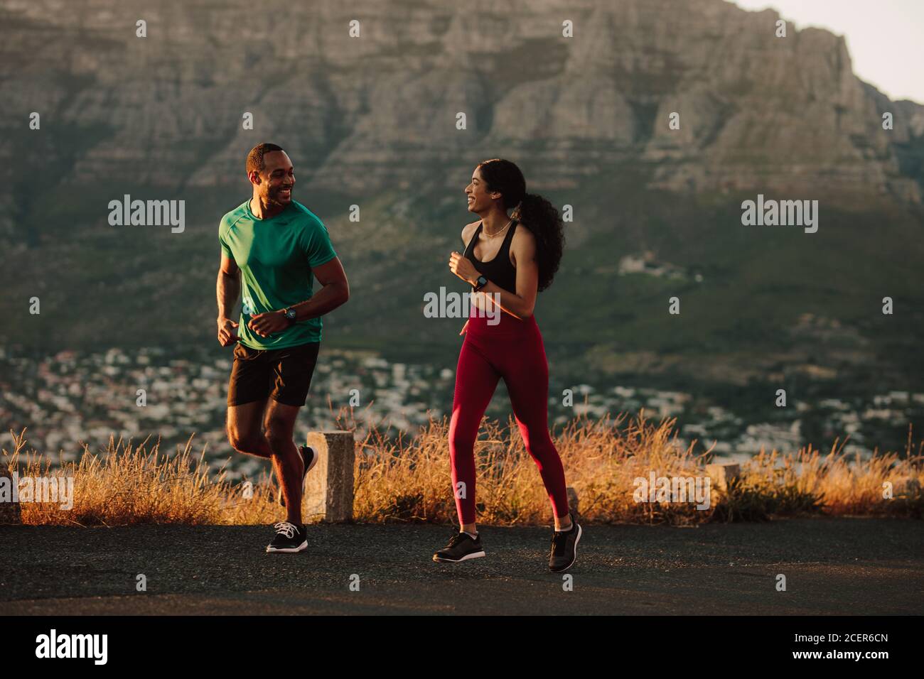 Fitness couple running on a highway with scenic mountains in the ...