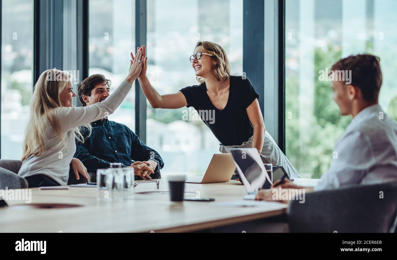 Female professional giving a high five to her colleague in conference ...