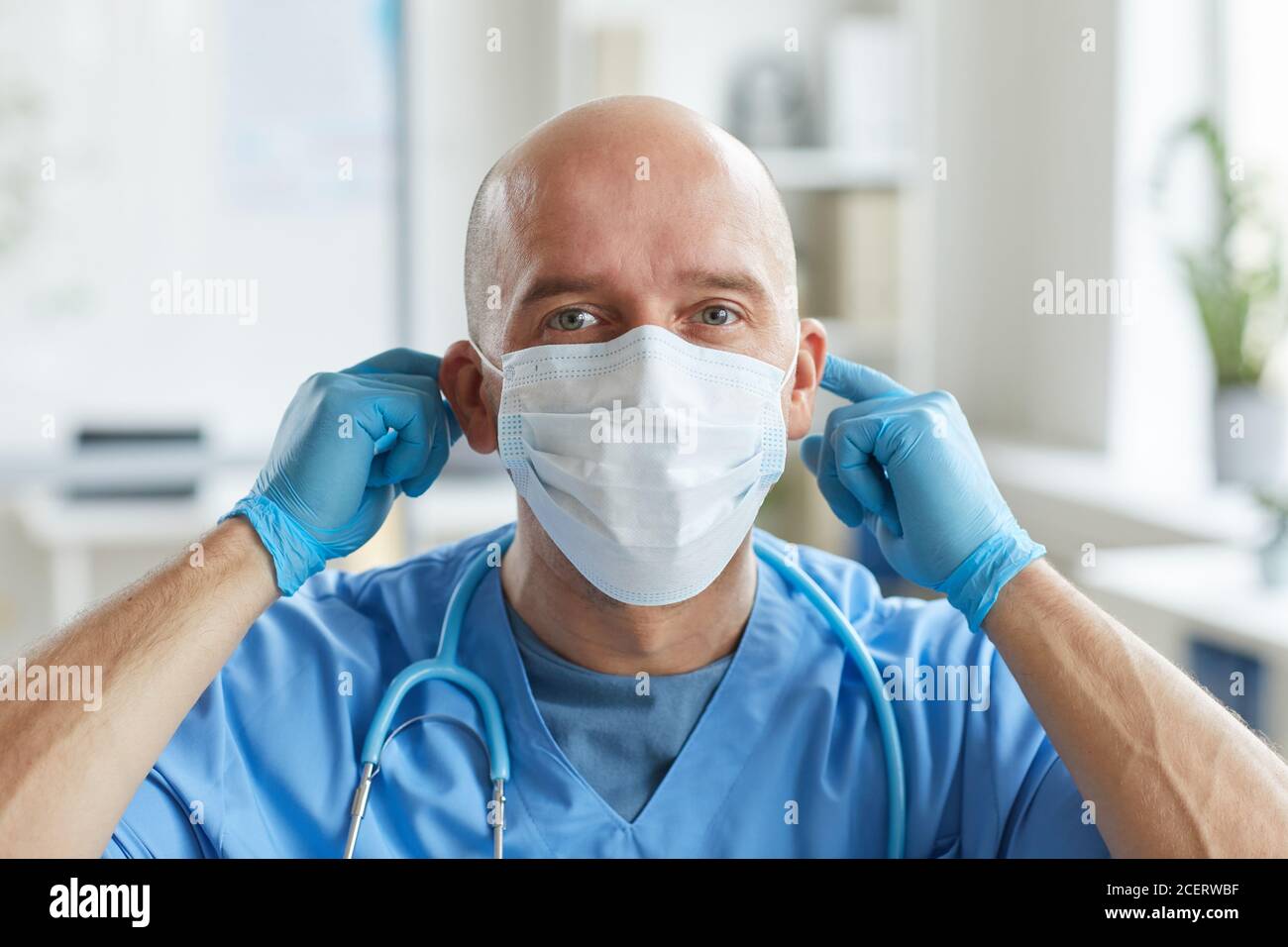 Professional doctor wearing blue uniform and latex gloves putting on ...