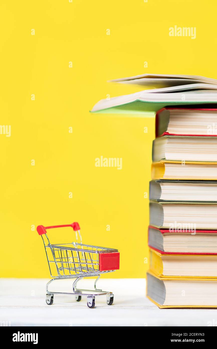 Back to school. A mini shopping cart and a stack of books with an open ...