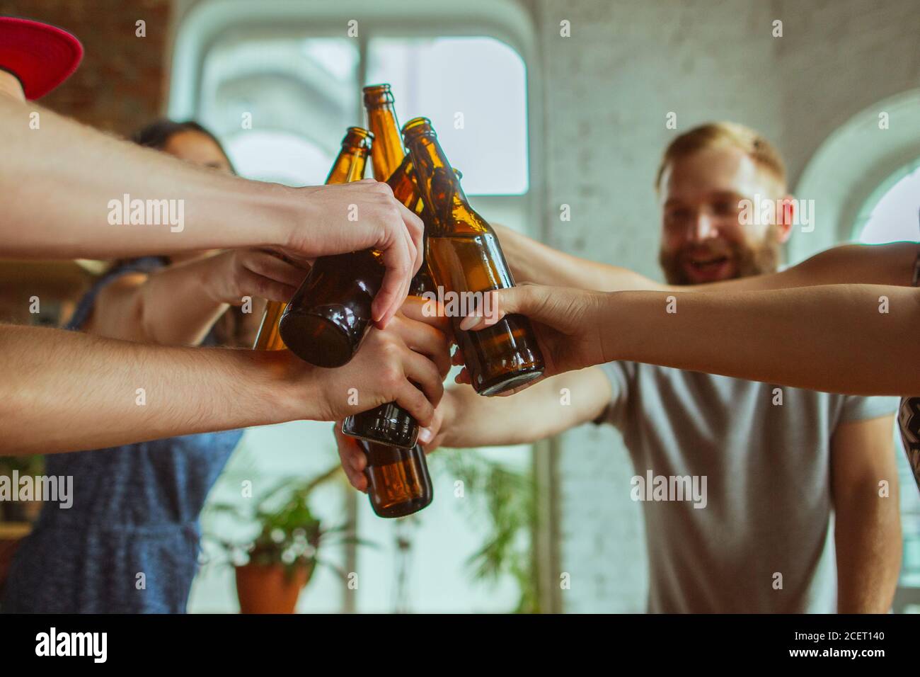Clinking bottles. Young group of friends drinking beer, having fun ...