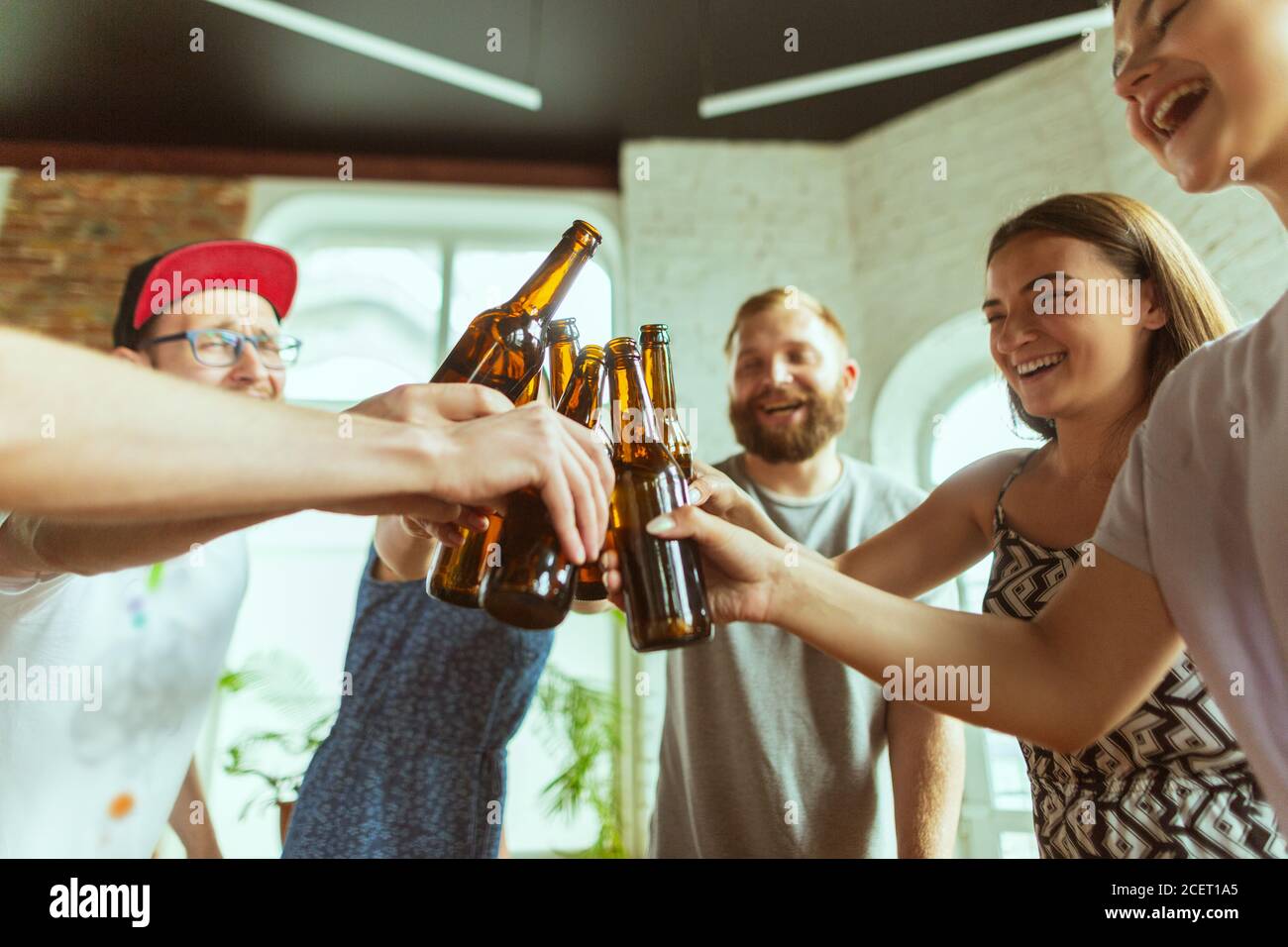 Clinking bottles. Young group of friends drinking beer, having fun ...
