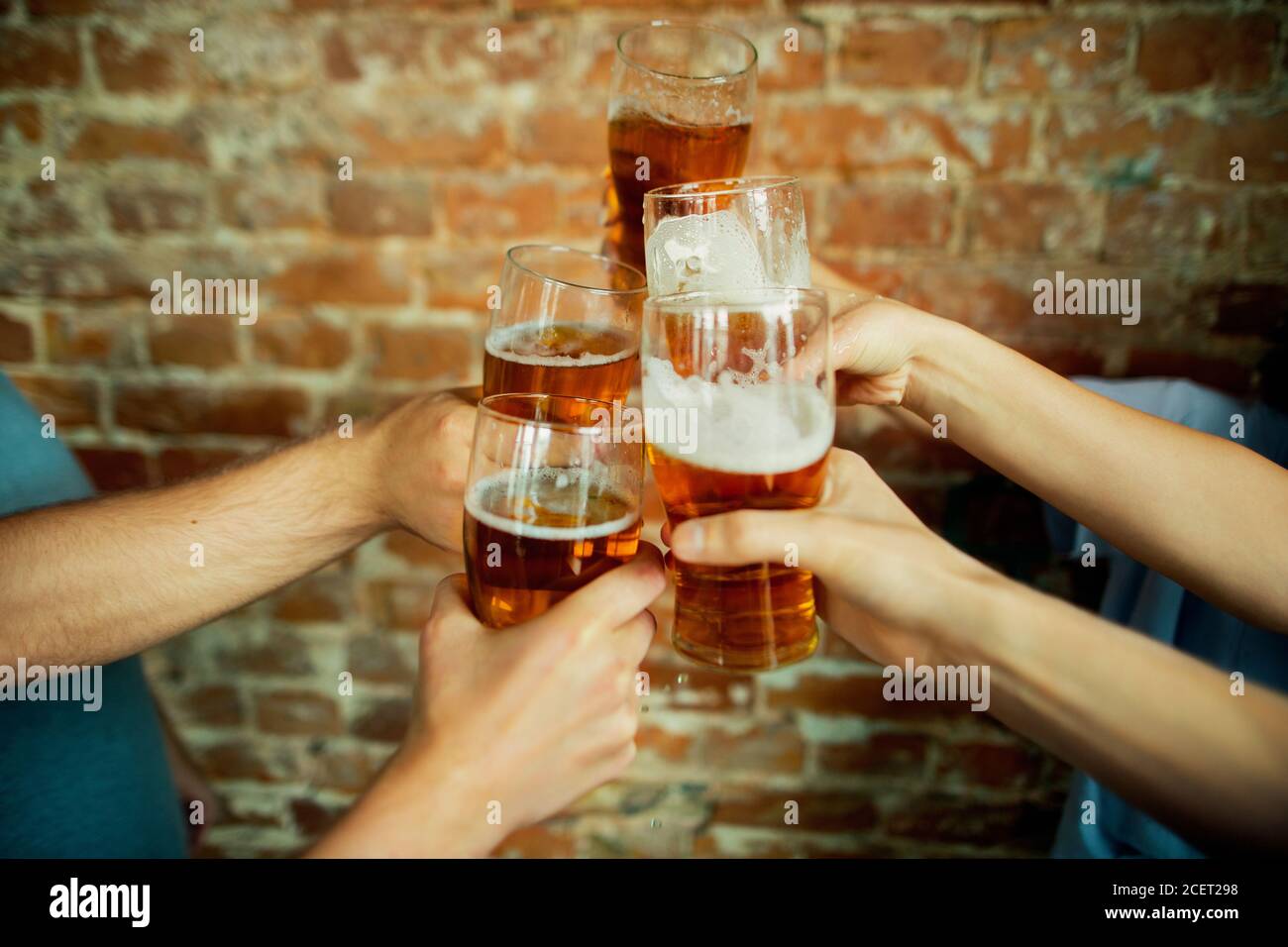 Close up clinking. Young group of friends drinking beer, having fun ...