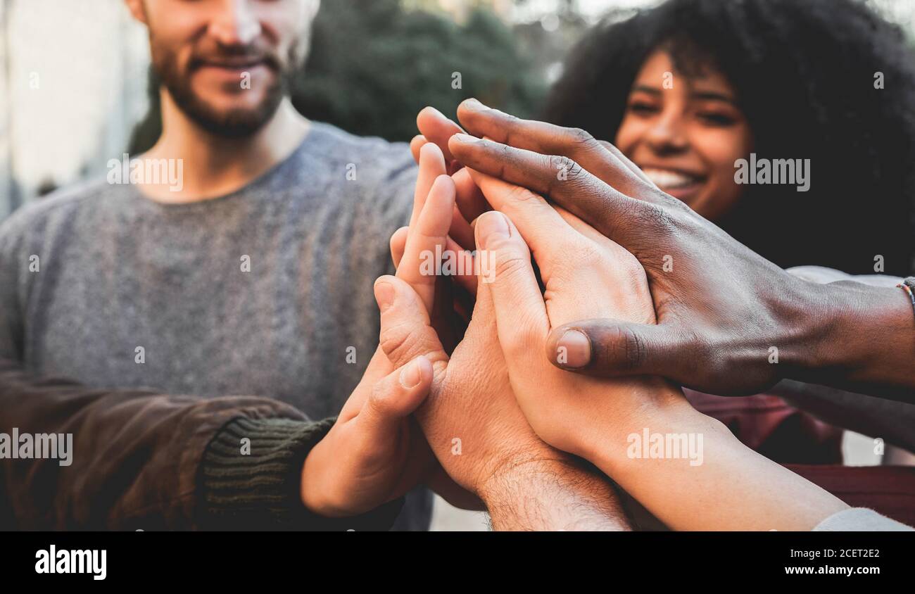 Young happy people stacking hands outdoor - Diverse culture students ...