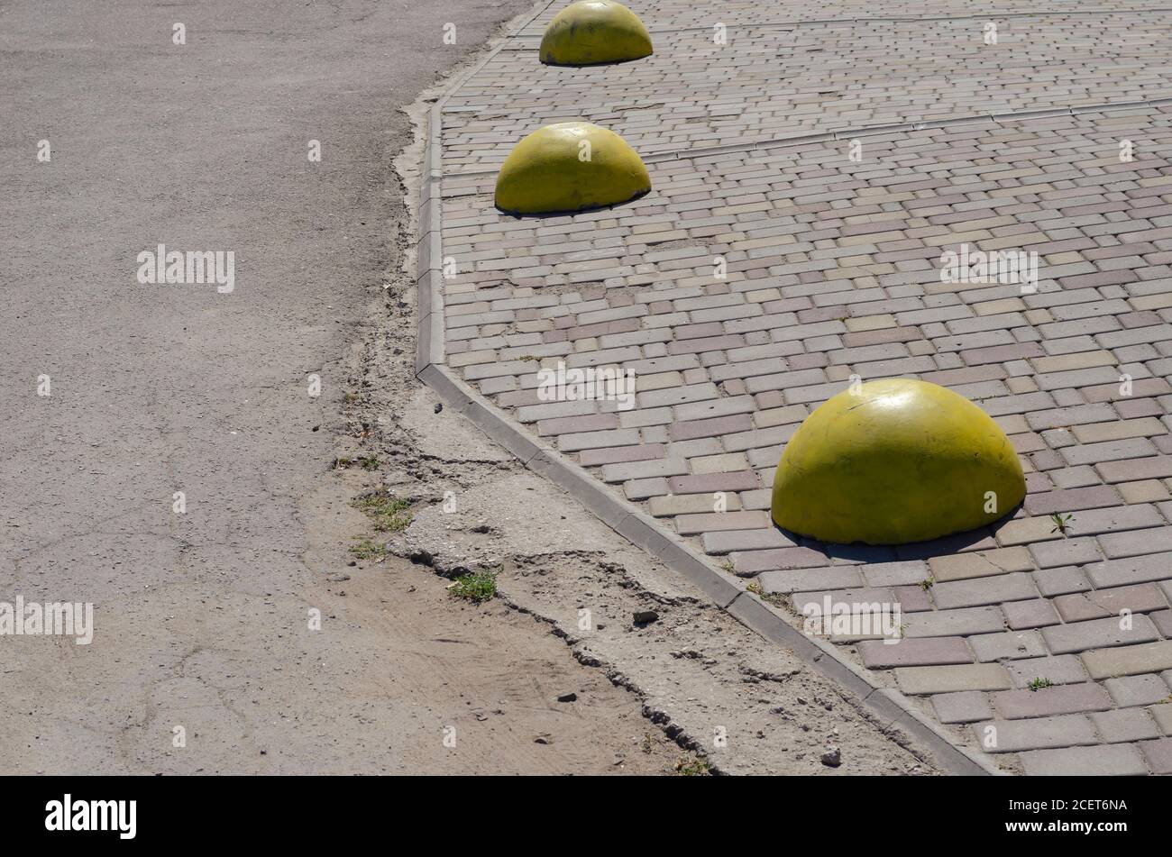 Three yellow concrete hemispheres at the edge of the sidewalk ...