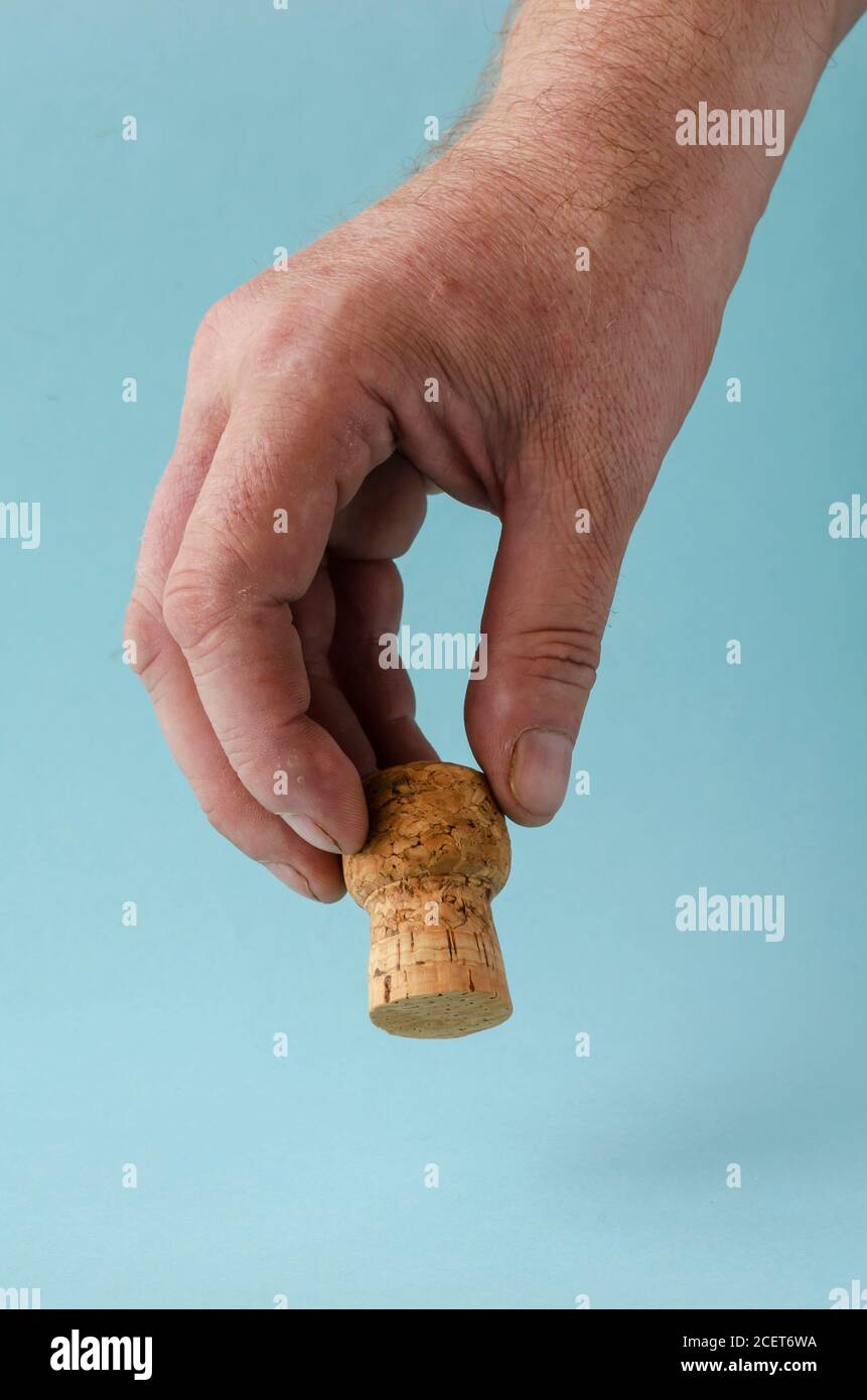 Male hand holds champagne cork. Adult Caucasian male with cork between ...