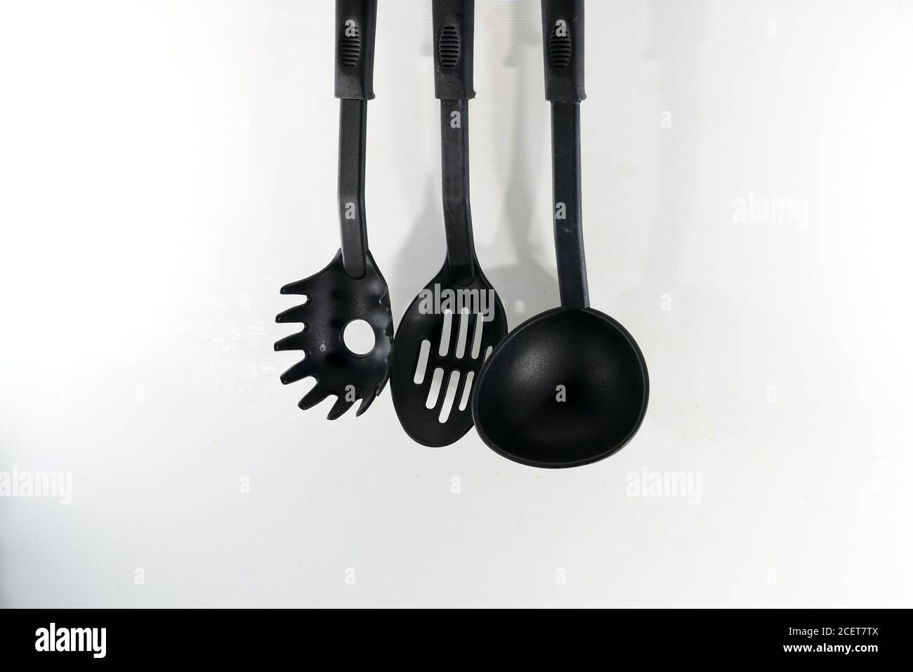 Set of black plastic kitchen utensils hanging on the white wall Stock ...