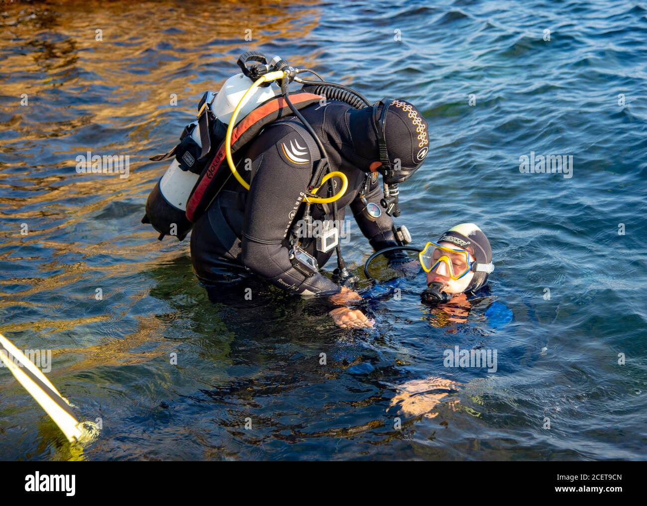 People in wetsuits and scuba gear are preparing to dive into the water ...