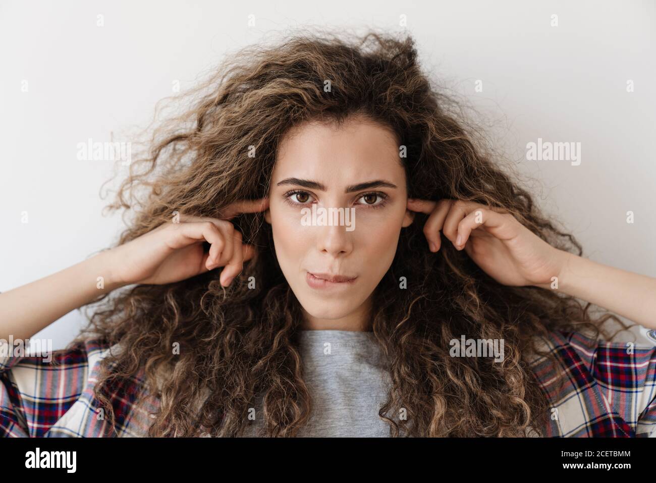 Photo of young beautiful woman plugging her ears while posing on camera ...