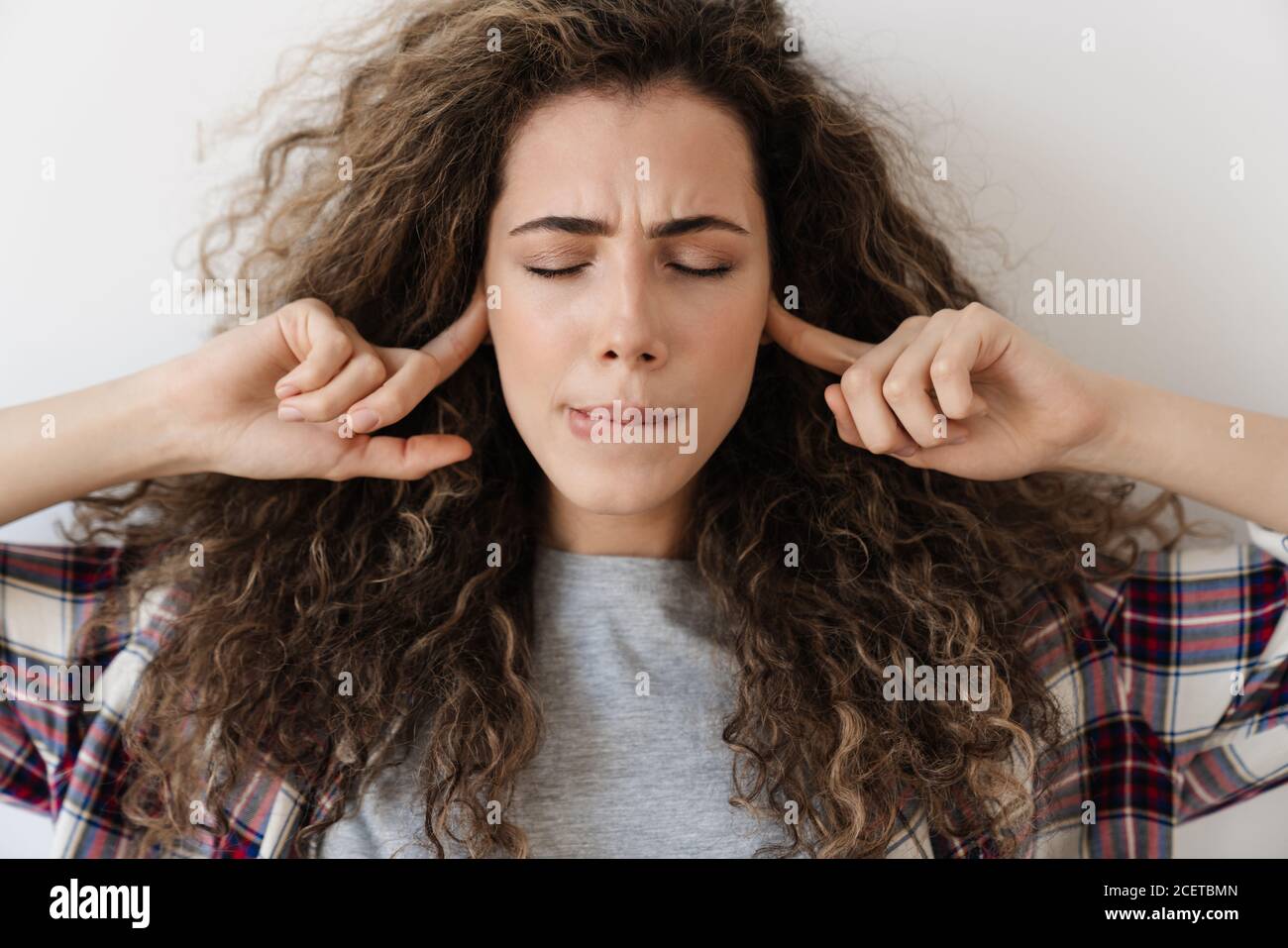 Photo of displeased beautiful woman plugging her ears while posing on ...