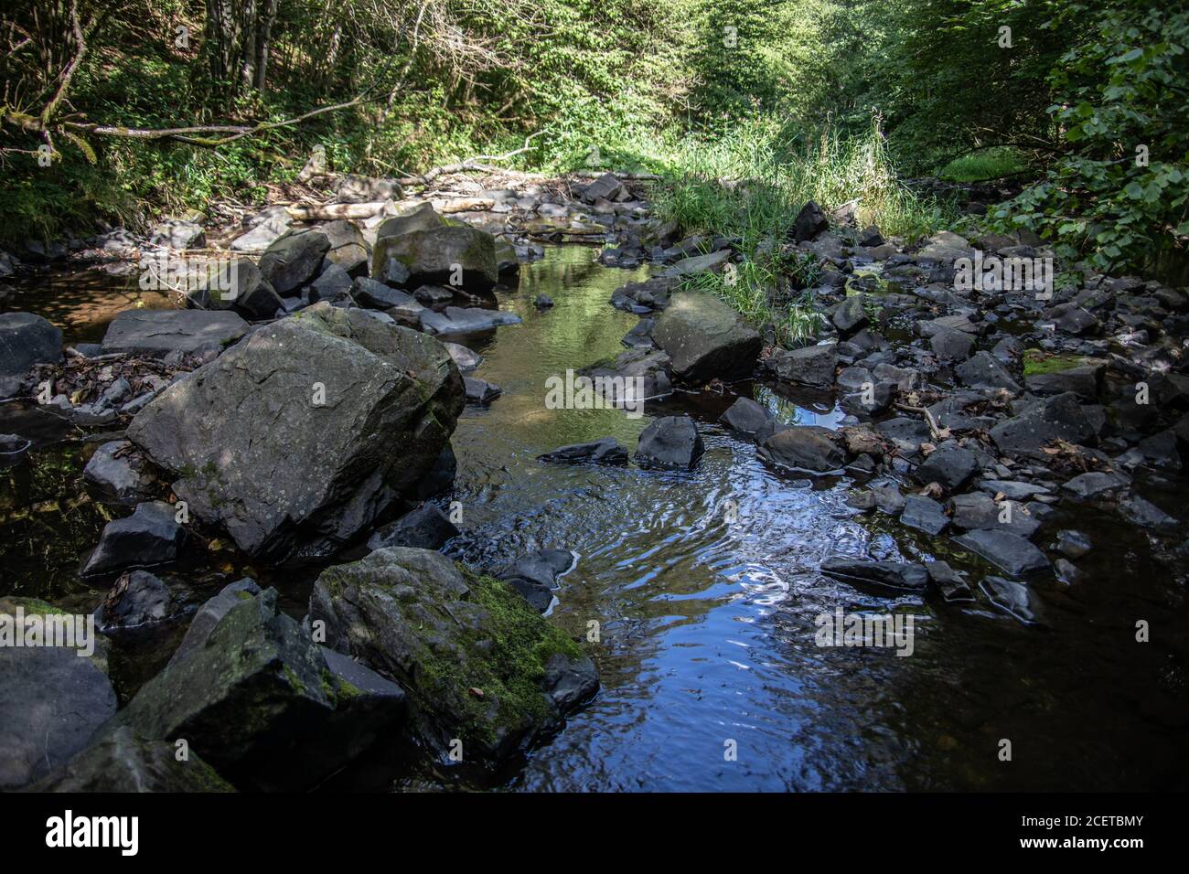 River course littered with rocks with waterfall in Siegerland Stock ...