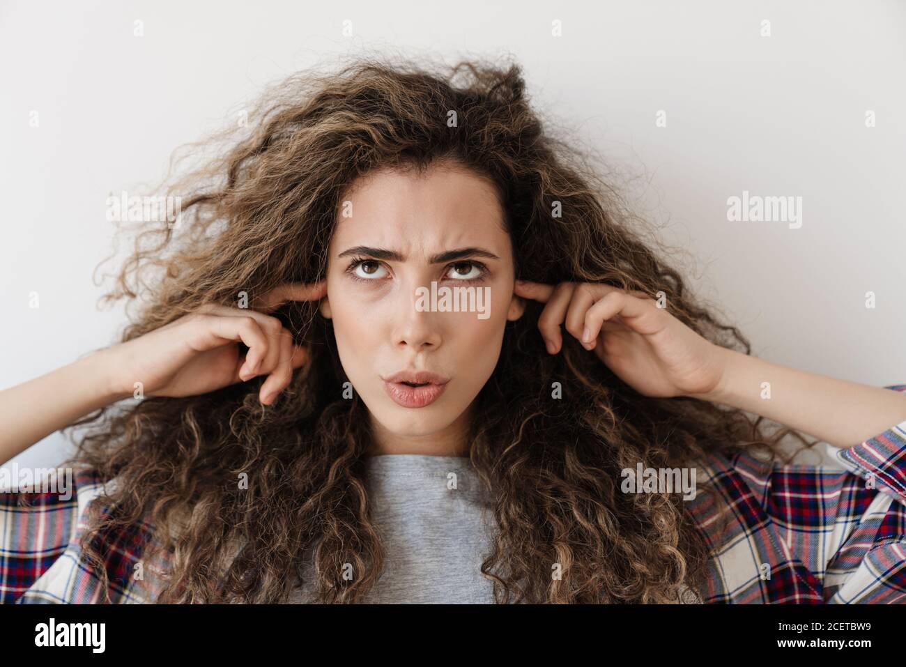 Photo of puzzled beautiful woman plugging her ears while posing on ...