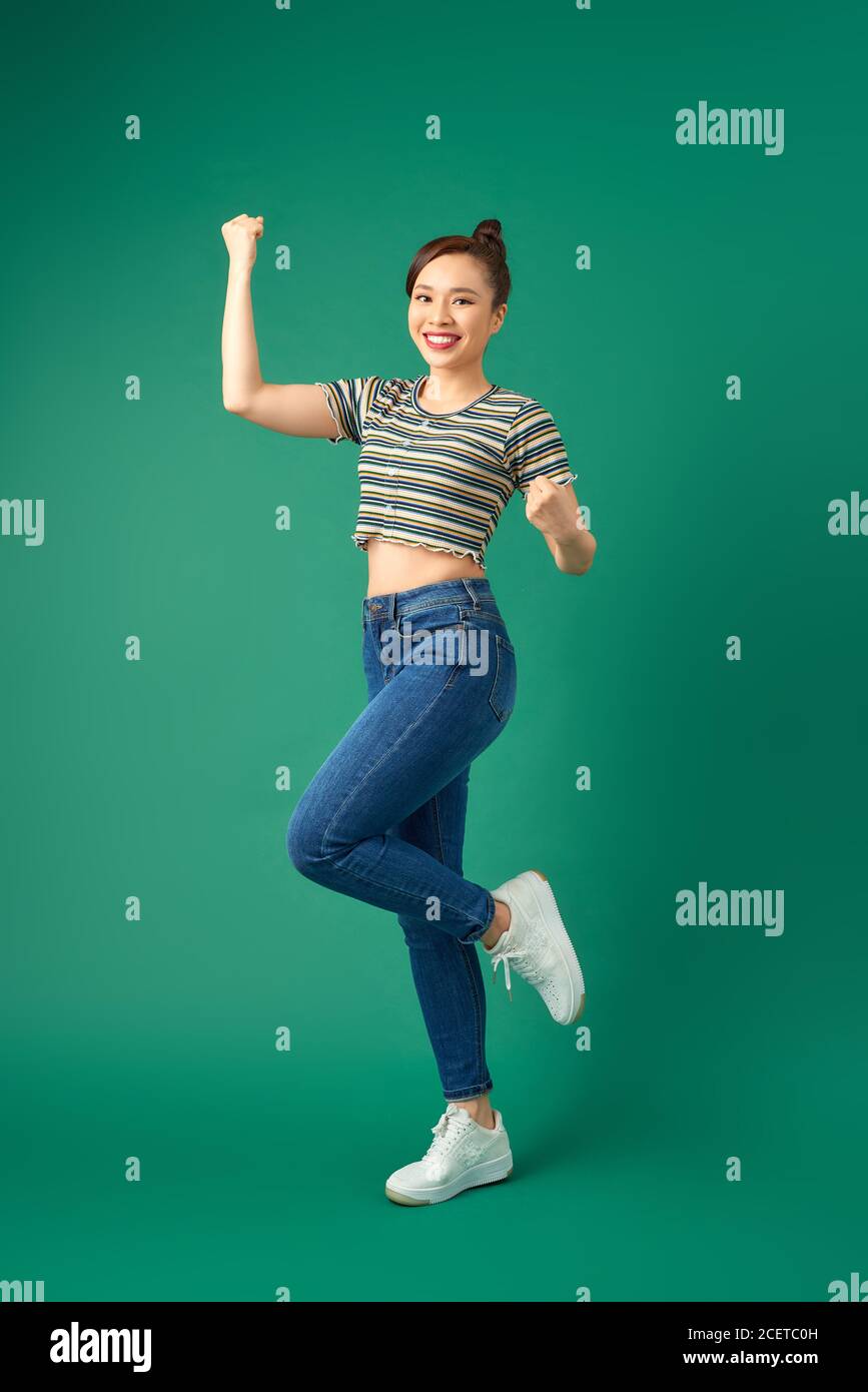 Full length portrait of happy young Asian woman standing on one leg and ...