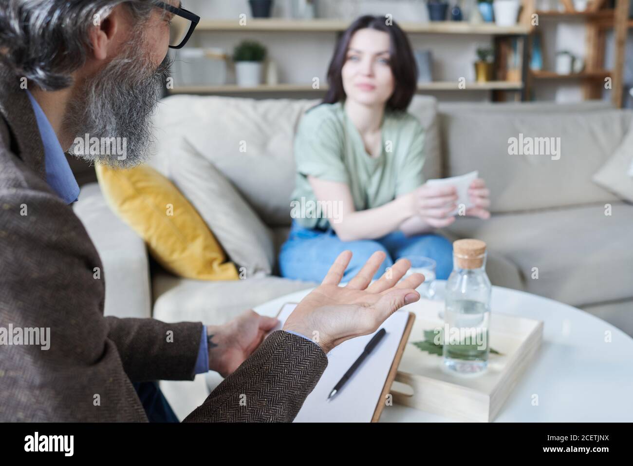 Psychologist sitting in front of young woman asking questions about her ...
