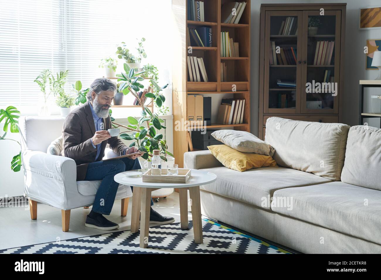 Modern psychologist reading notes and drinking coffee while waiting for ...