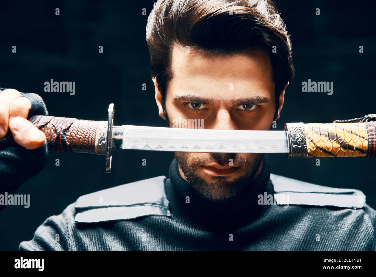 Warrior man posing with a sword isolated on black background. Close up ...