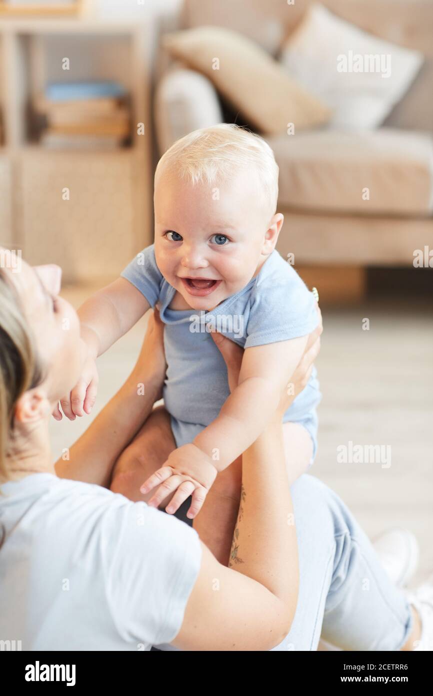 Vertical over-the-shoulder shot of mother spending time at home playing ...