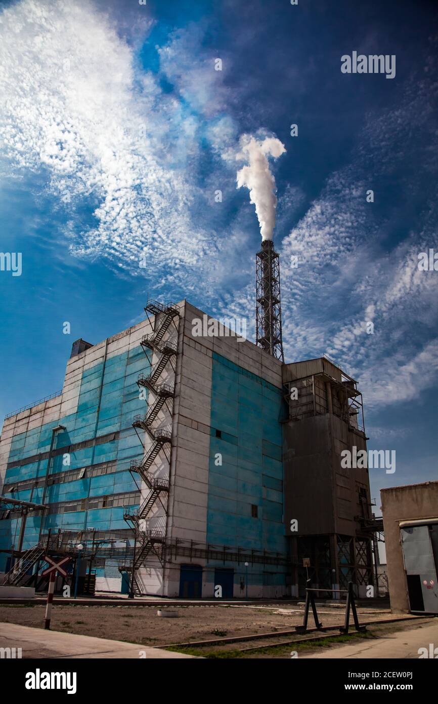 Smoking factory chimney with white smoke. Blue factory building with ...