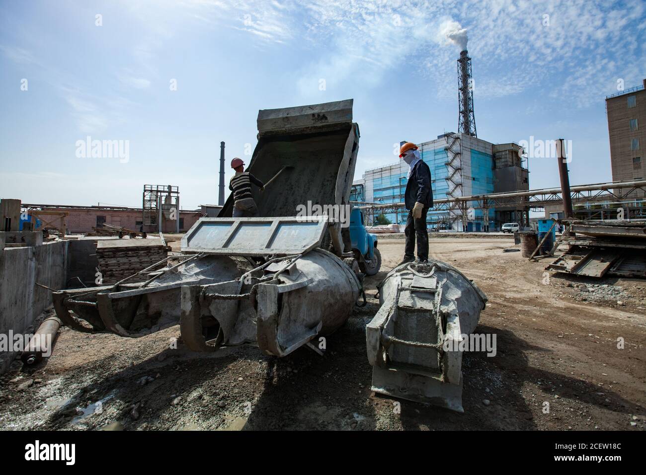 Grey cement dump truck and workers in orange hardhats, smoking chimney ...