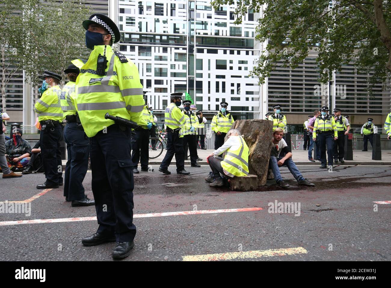 Police officers surround Extinction Rebellion protesters who are glued ...
