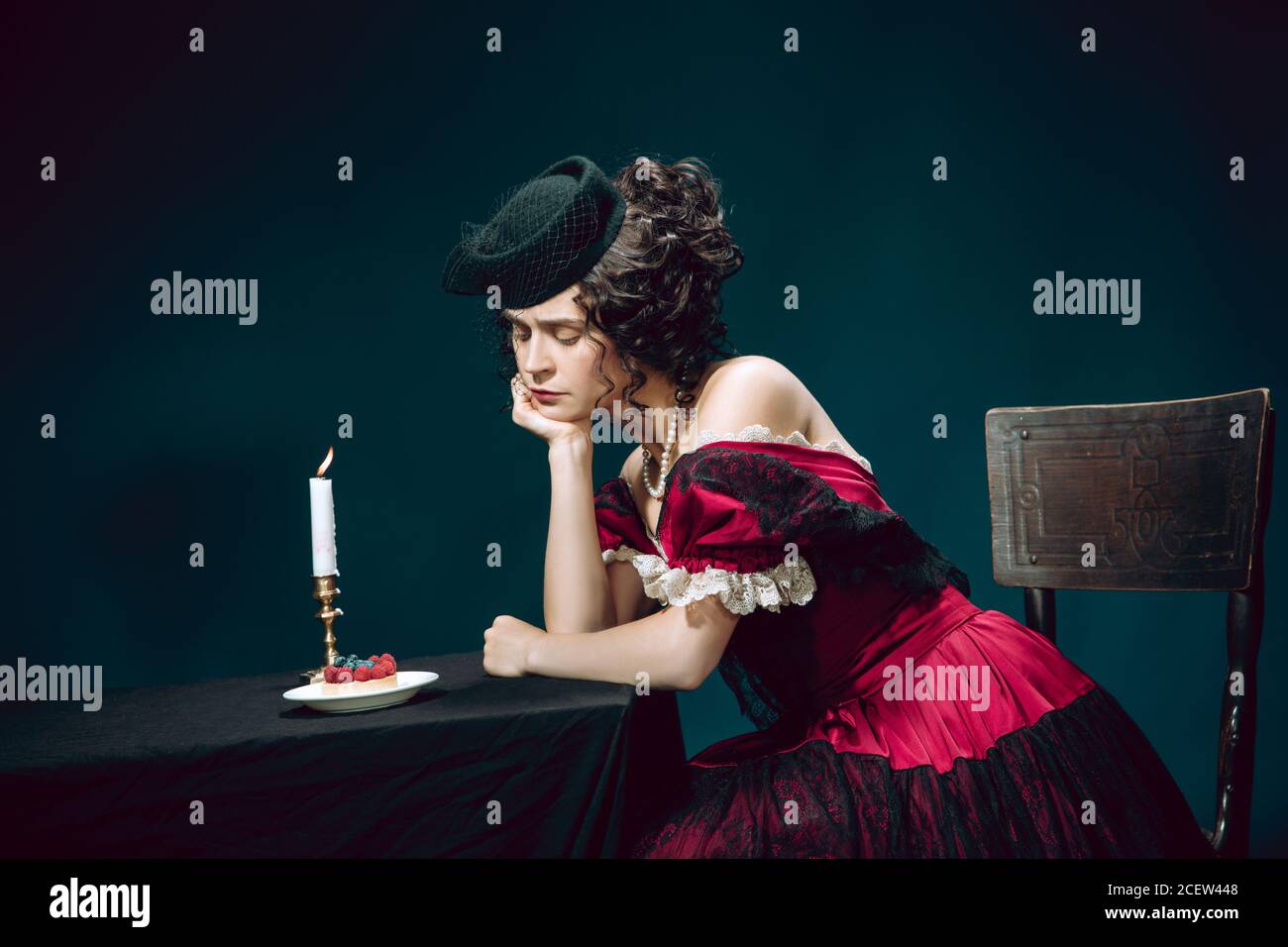 Diet and sweets. Young woman as Anna Karenina isolated on dark blue ...