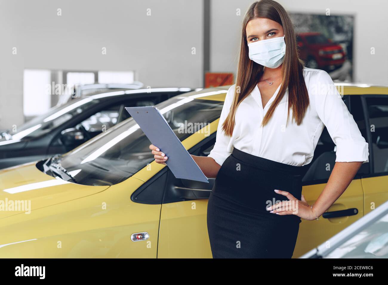 Woman car seller standing near new car wearing protective face mask ...