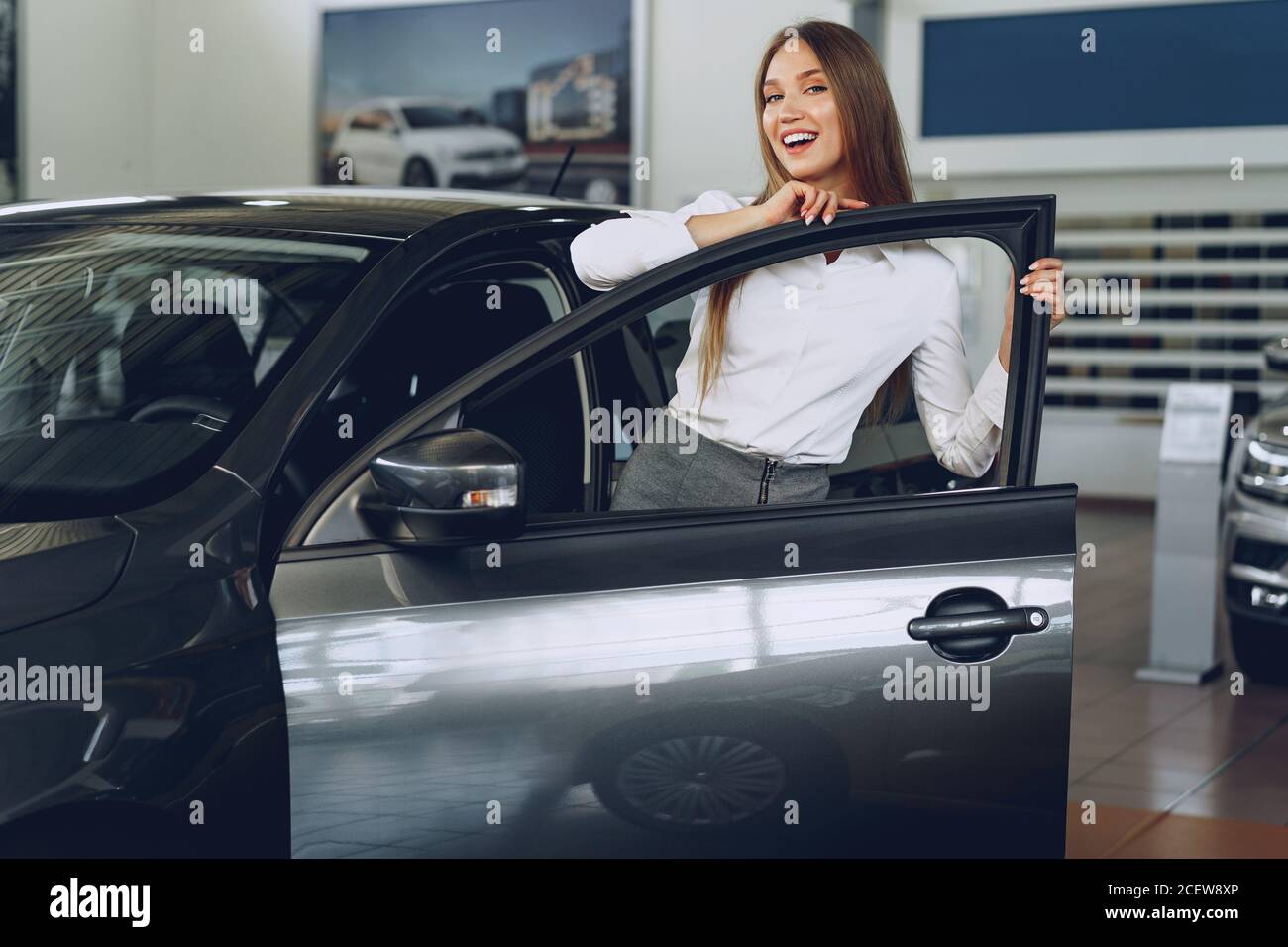 Beautiful young woman touching her new car with pleasure Stock Photo ...