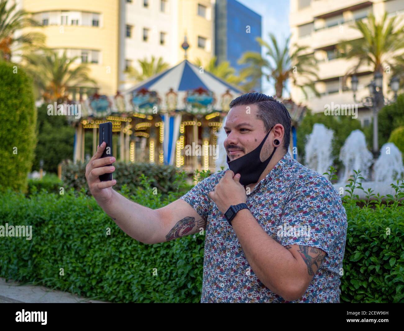 Male pulling down his medical mask to video call with his smartphone ...