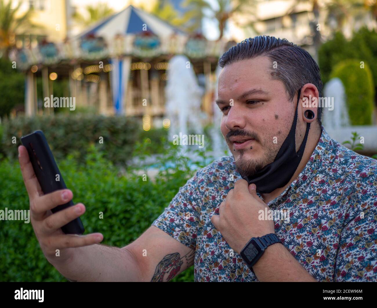Male pulling down his medical mask to video call with his smartphone ...