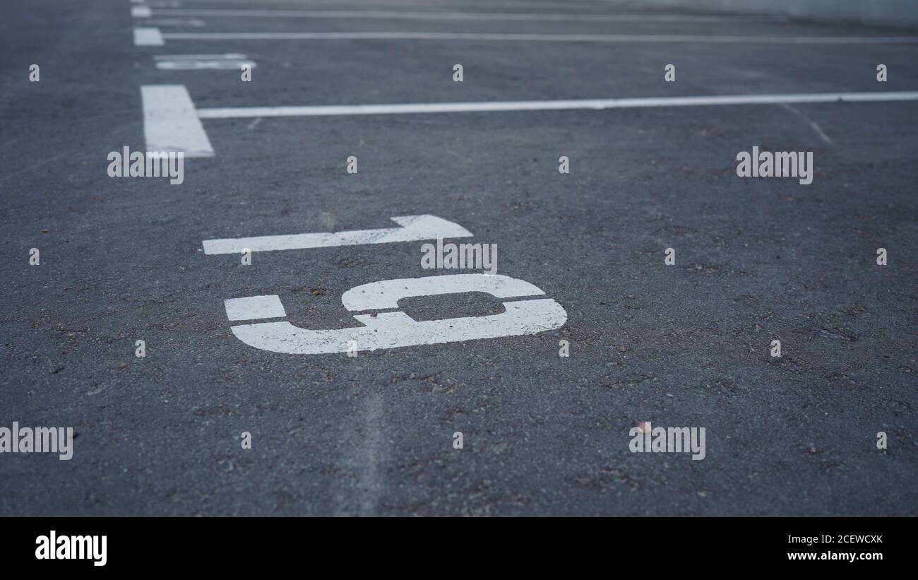 Close-up of a white paint number marking in a parking lot. Empty ...