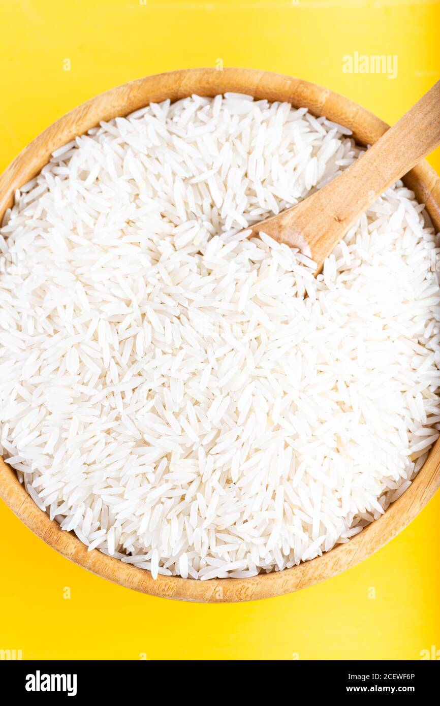 Wooden bowl full of basmati rice on wooden background Stock Photo - Alamy