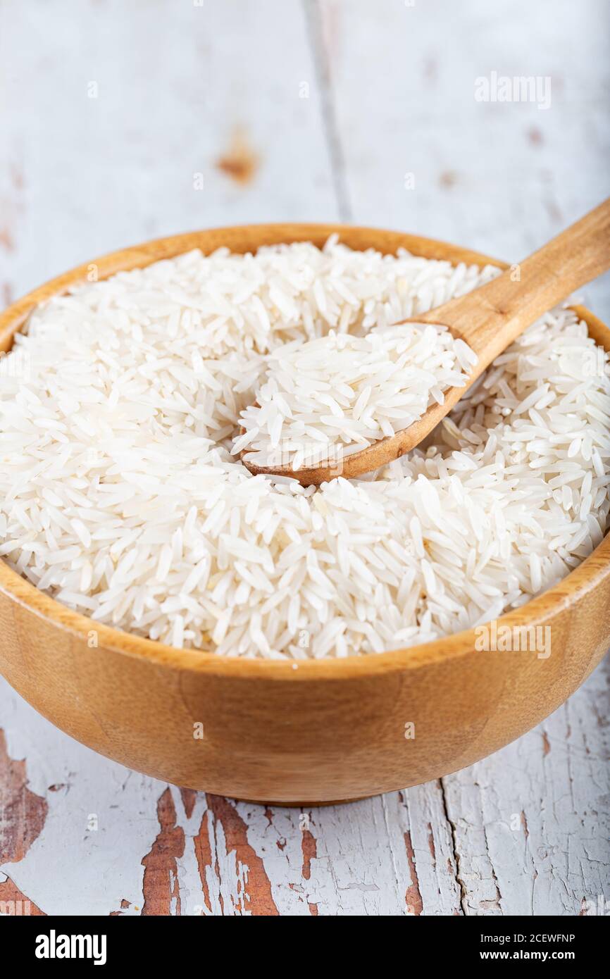 Wooden bowl full of basmati rice on wooden background Stock Photo - Alamy