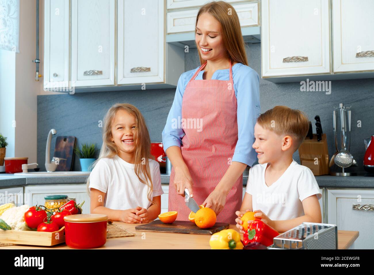Mother cooking with her children in kitchen Stock Photo - Alamy