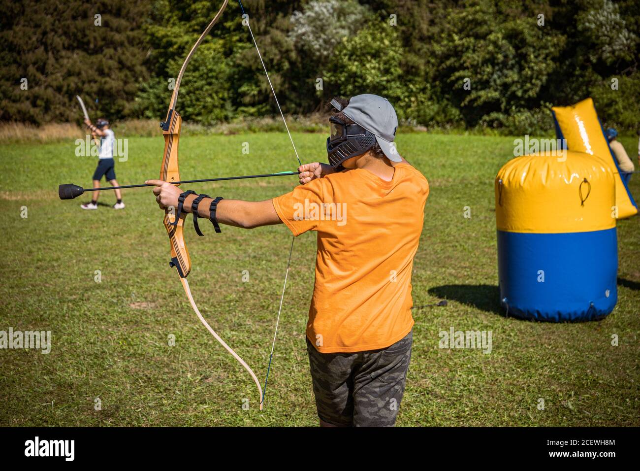 Teenage boy playing archery tag on a meadow Stock Photo - Alamy