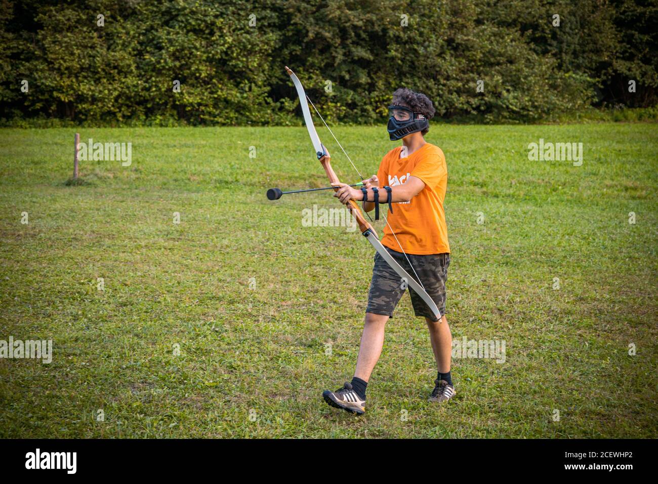 Teenage boy playing archery tag on a meadow Stock Photo - Alamy