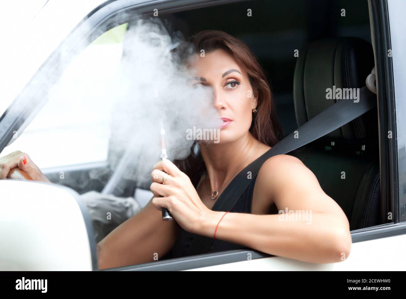 Pretty woman smoking the e-cigarette while driving a car Stock Photo ...