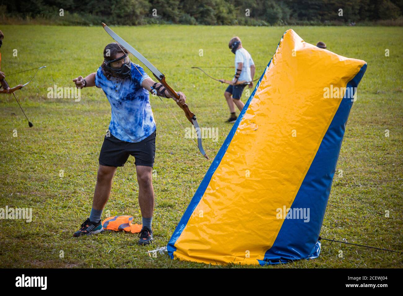 Teenage boy playing archery tag on a meadow Stock Photo - Alamy