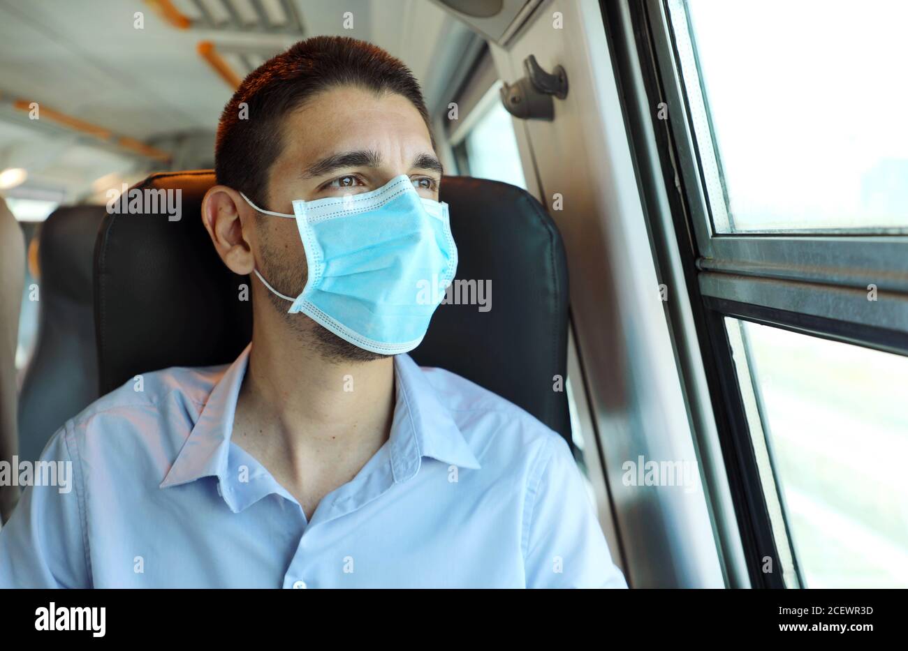 Travel safely on public transport. Young man with surgical mask looking ...