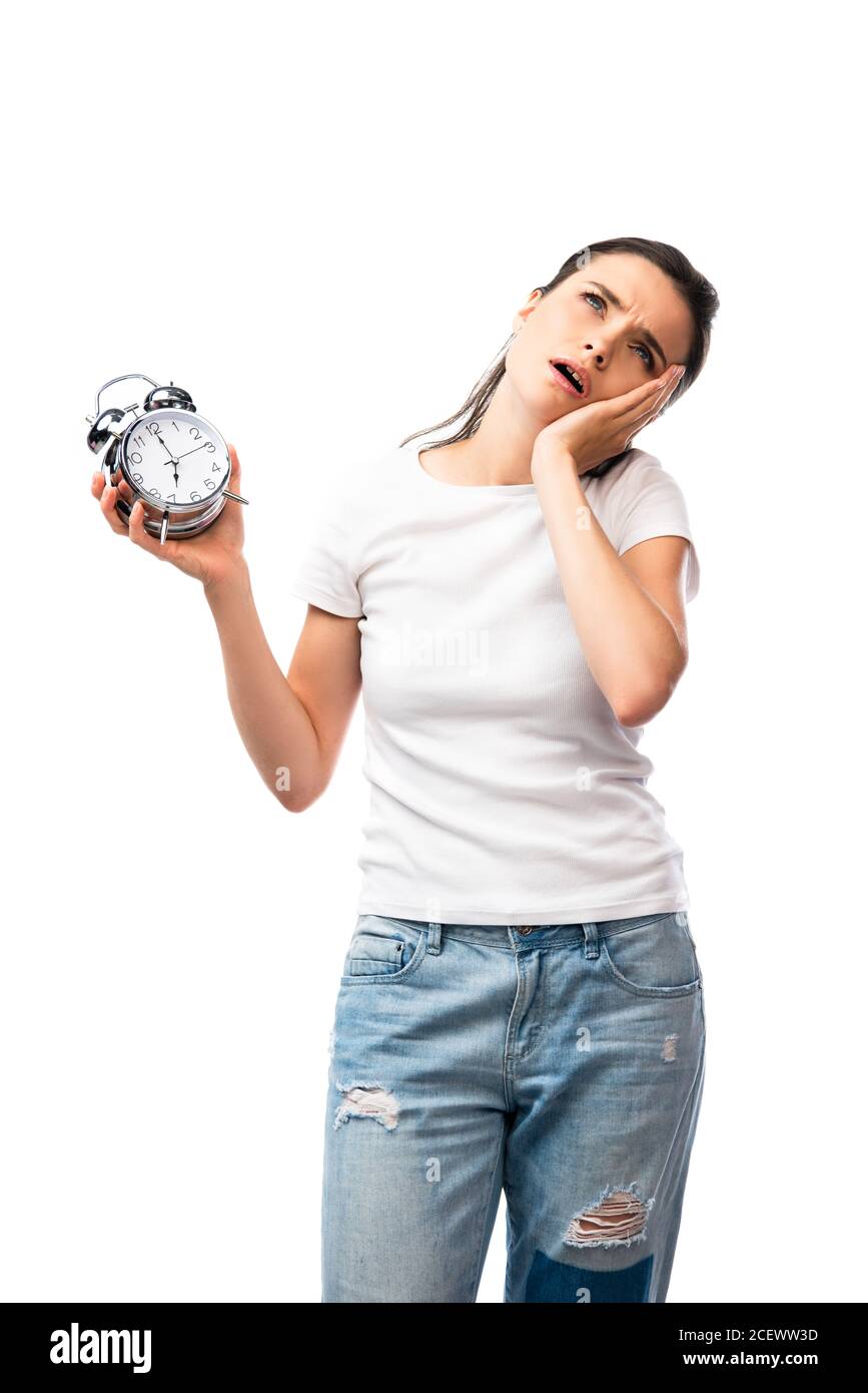 tired brunette woman in white t-shirt and jeans holding retro alarm ...