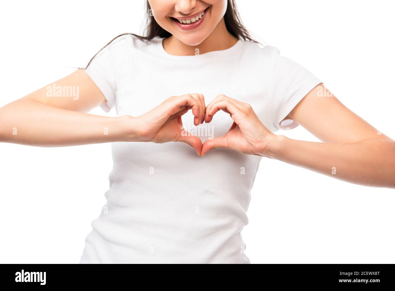 cropped view of young woman showing heart sign with hands isolated on ...
