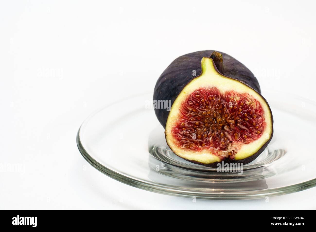 a half fig fruit with red seeds on a glass plate Stock Photo - Alamy