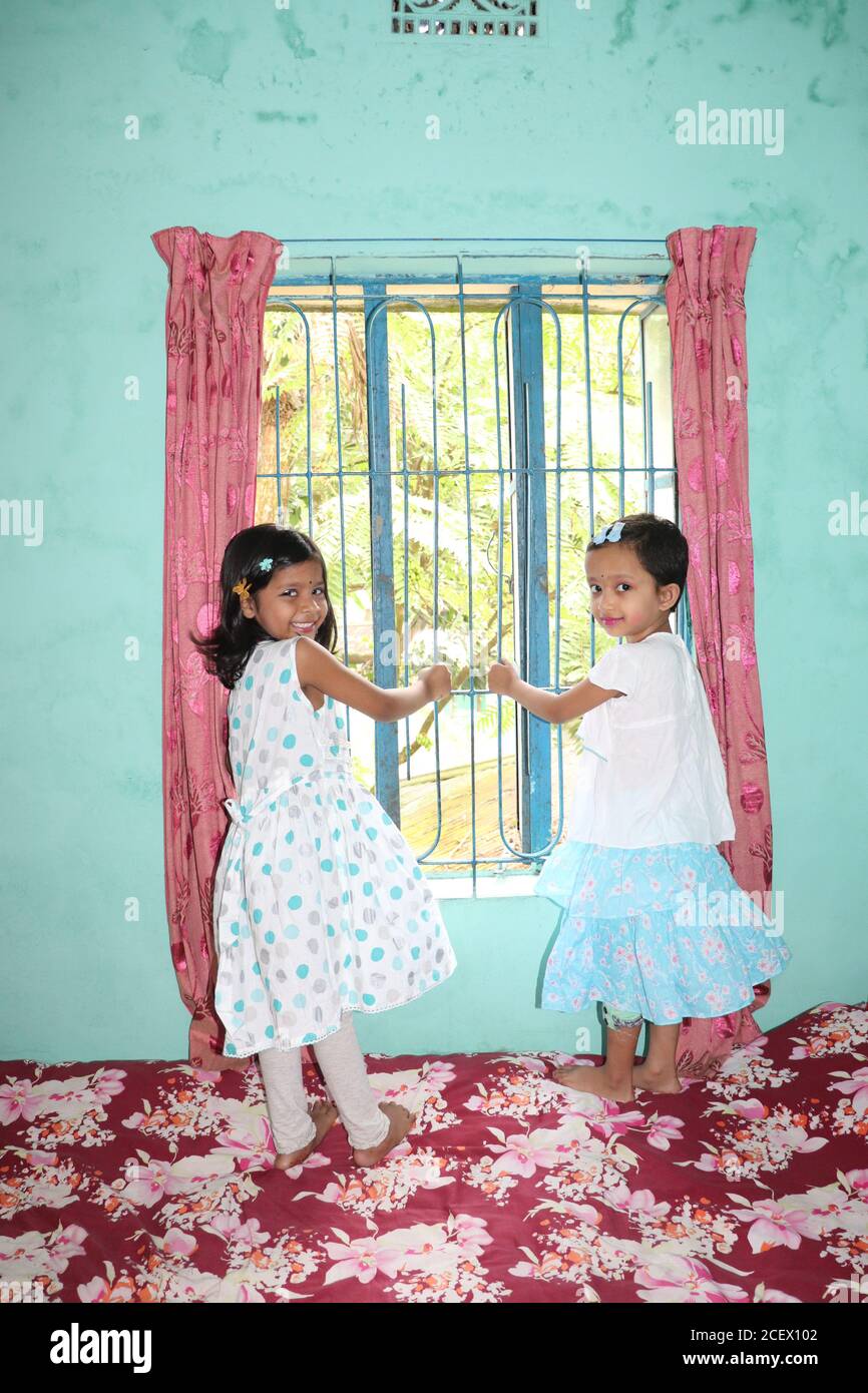Two girl kids playing in the window Stock Photo - Alamy