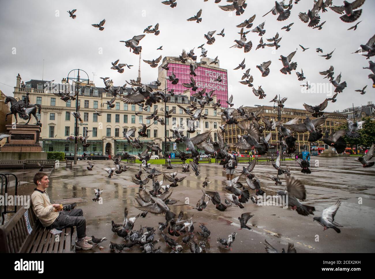 A man feeds the pigeons in George Square in Glasgow city centre Stock ...