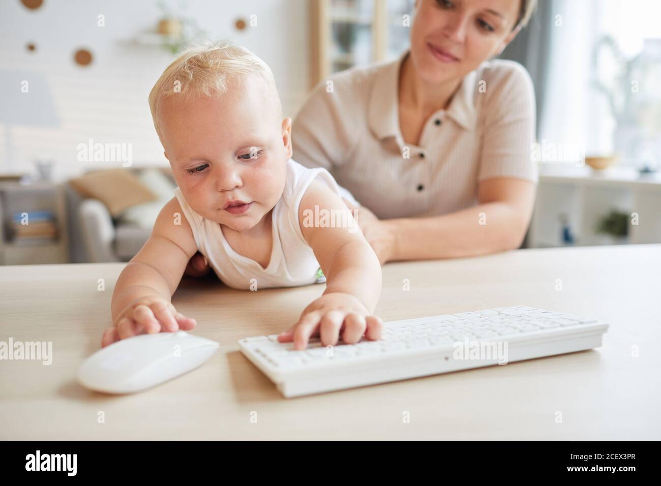 Lovely little baby playing with computer keyboard while his mother ...