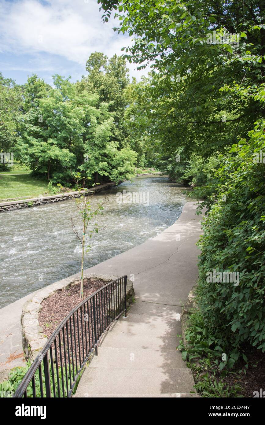 Ramp to the riverwalk path along the flowing DuPage River with lush ...