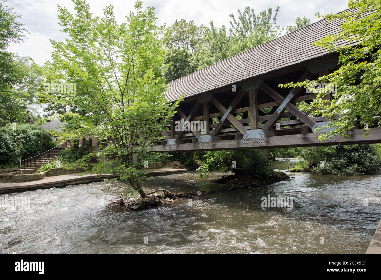 Covered bridge crossing the flowing DuPage River with footpath and ...