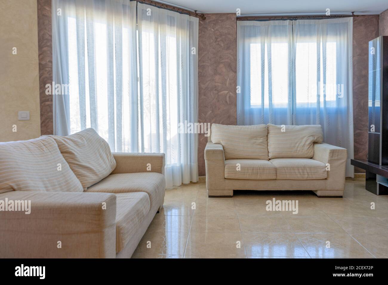 View of a spacious living room with lots of light beige sofas and two ...