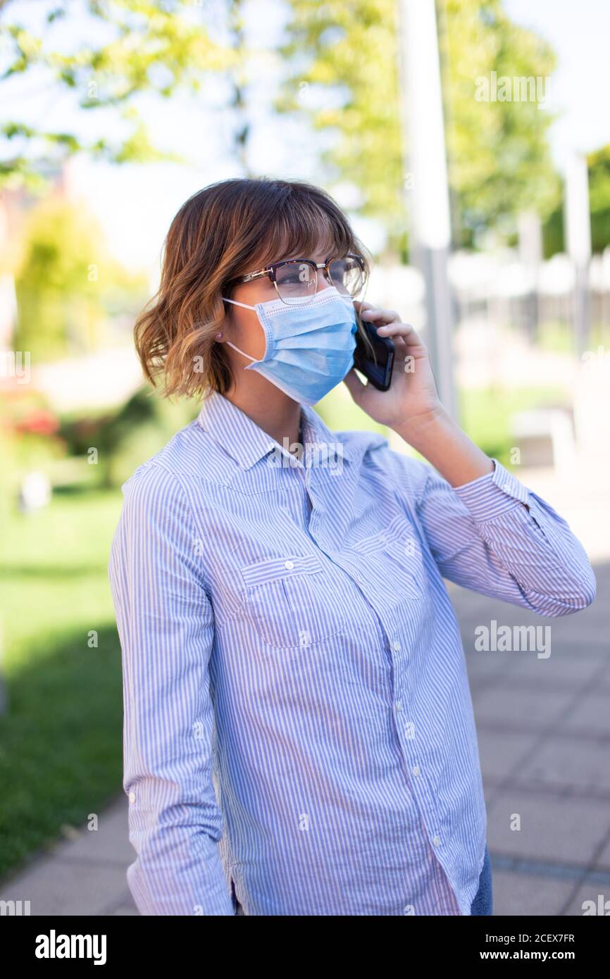 Young CEO in mask and eyeglasses calling in park outdoors Stock Photo ...