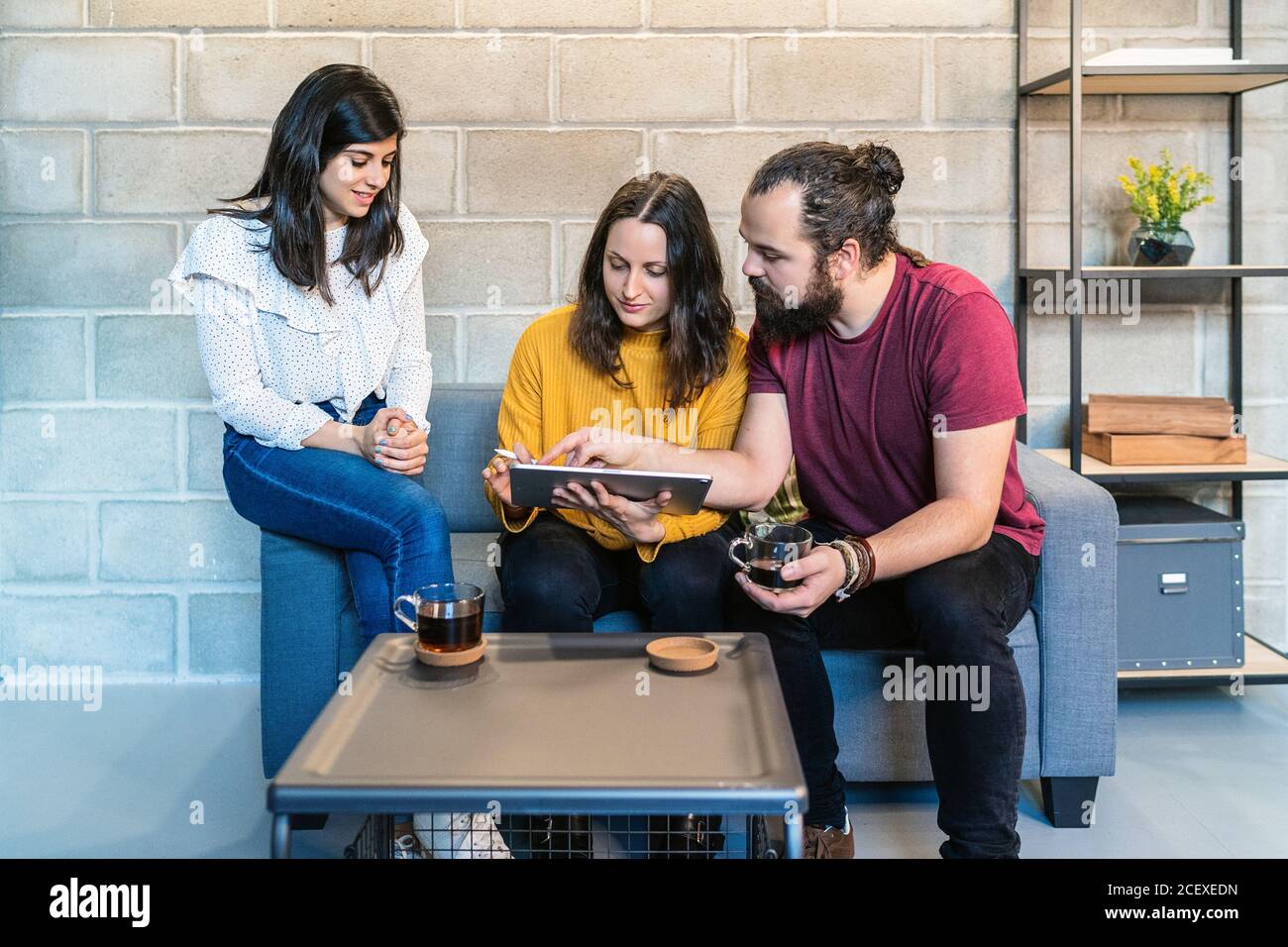 Group of creative millennial designers drinking coffee and discussing ...